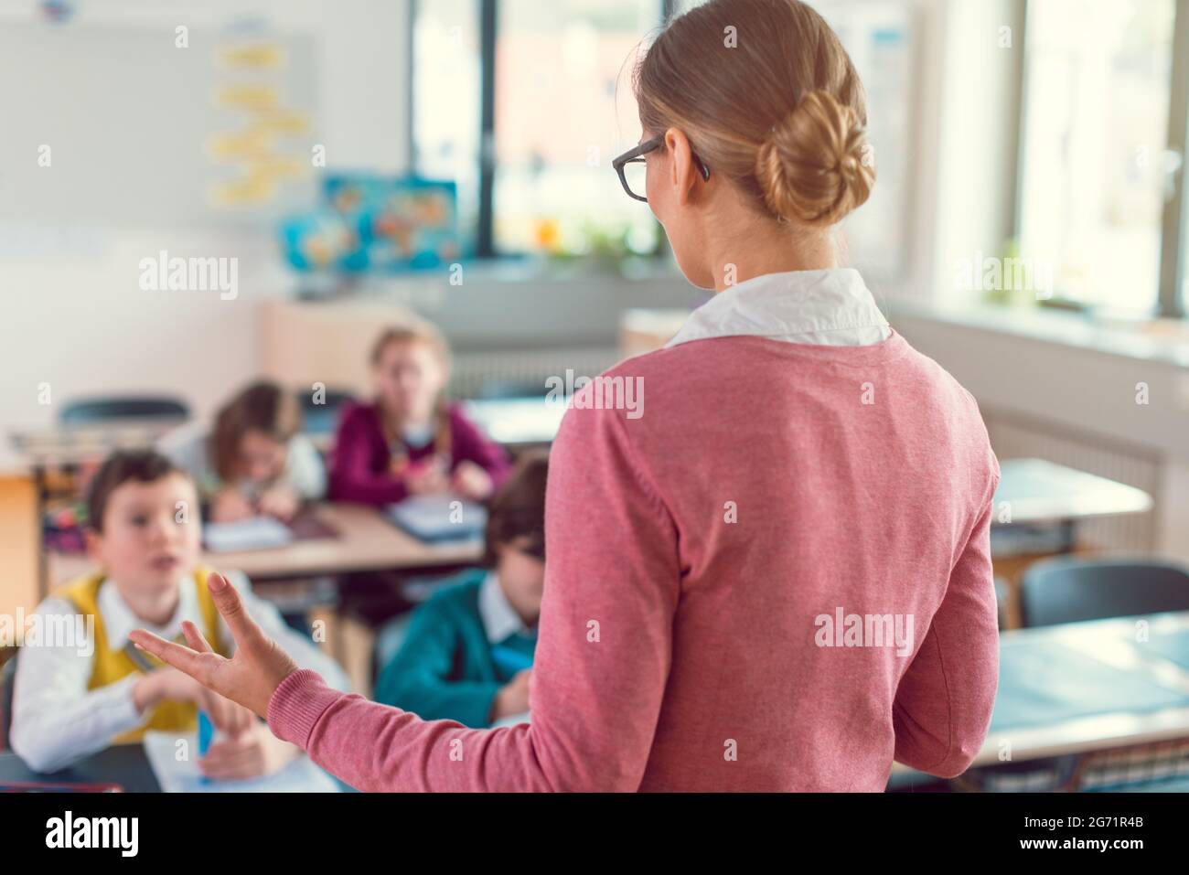 Teacher with her students in class at elementary school giving them an ...