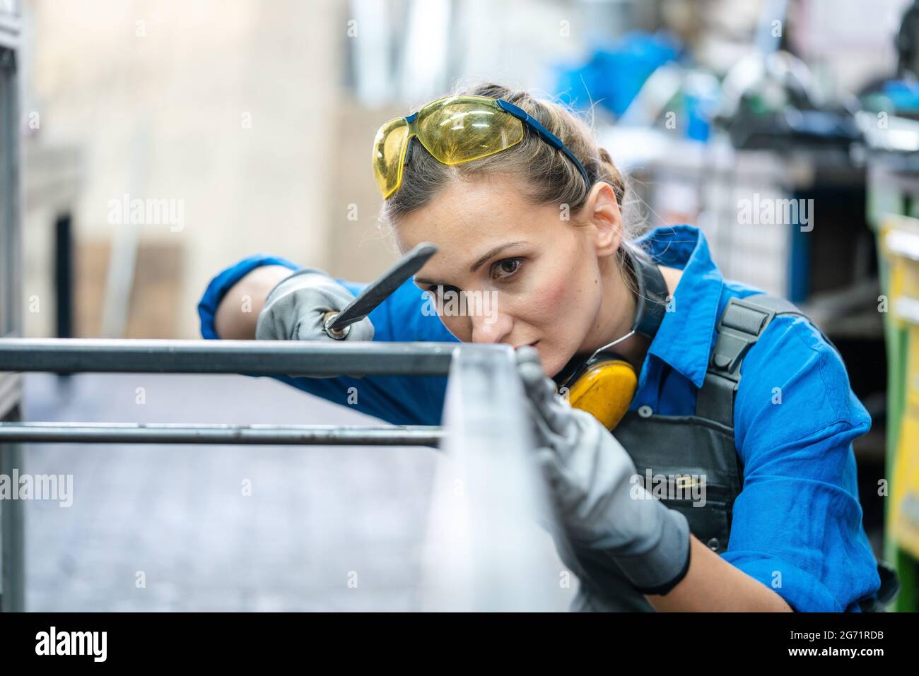 Woman metalworker checking the accuracy of her work holding steel file ...