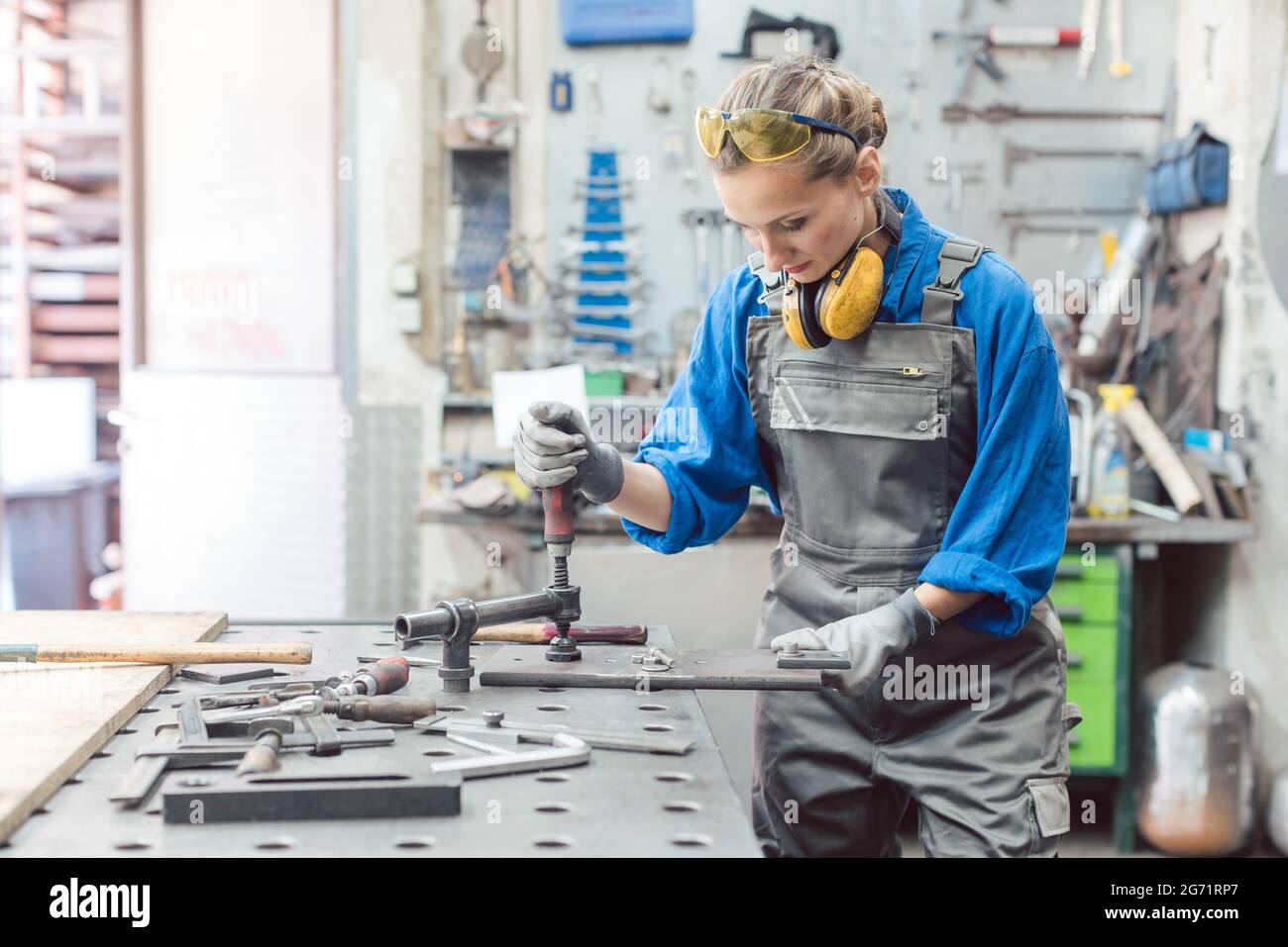 Female mechanic working with clamp and spanner on metal workpiece Stock ...