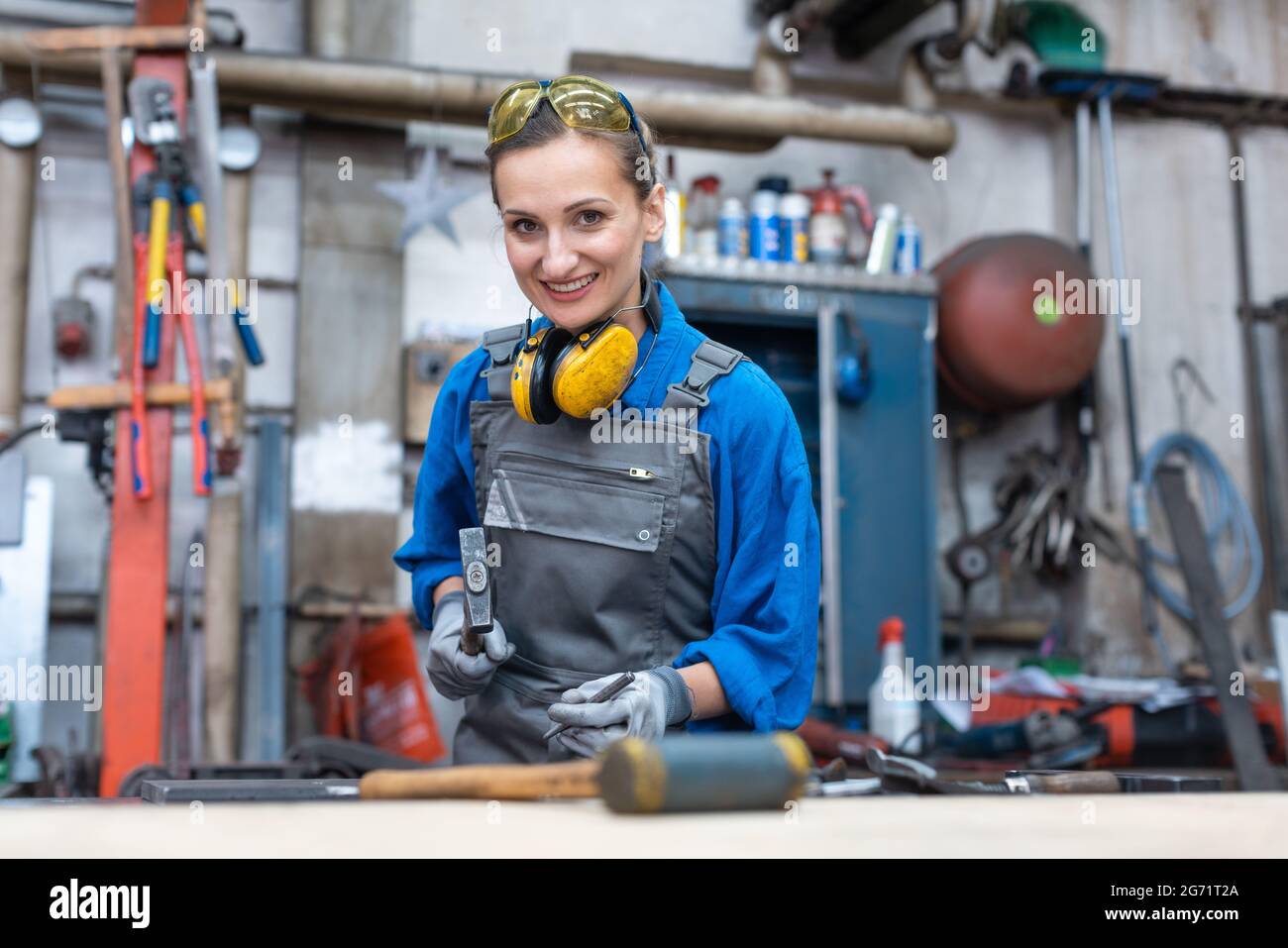 Woman worker marking workpiece in her workshop looking into camera ...