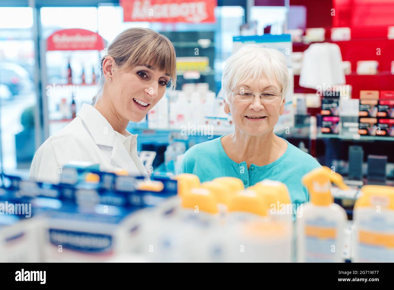 Chemist and customer standing in pharmacy between the shelves talking ...