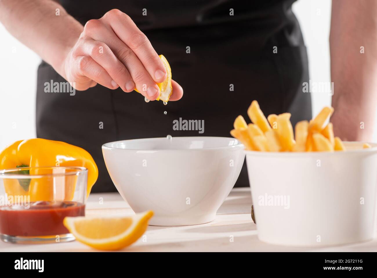 Hand squeezing lemon juice into a bowl with ingredients Stock Photo - Alamy