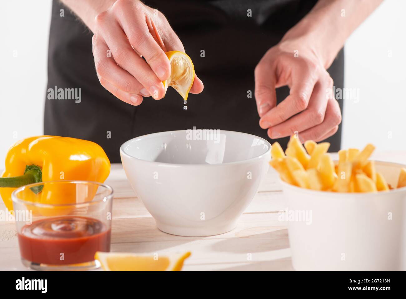 Hands squeezing a lemon slice into a bowl with ingredients Stock Photo ...