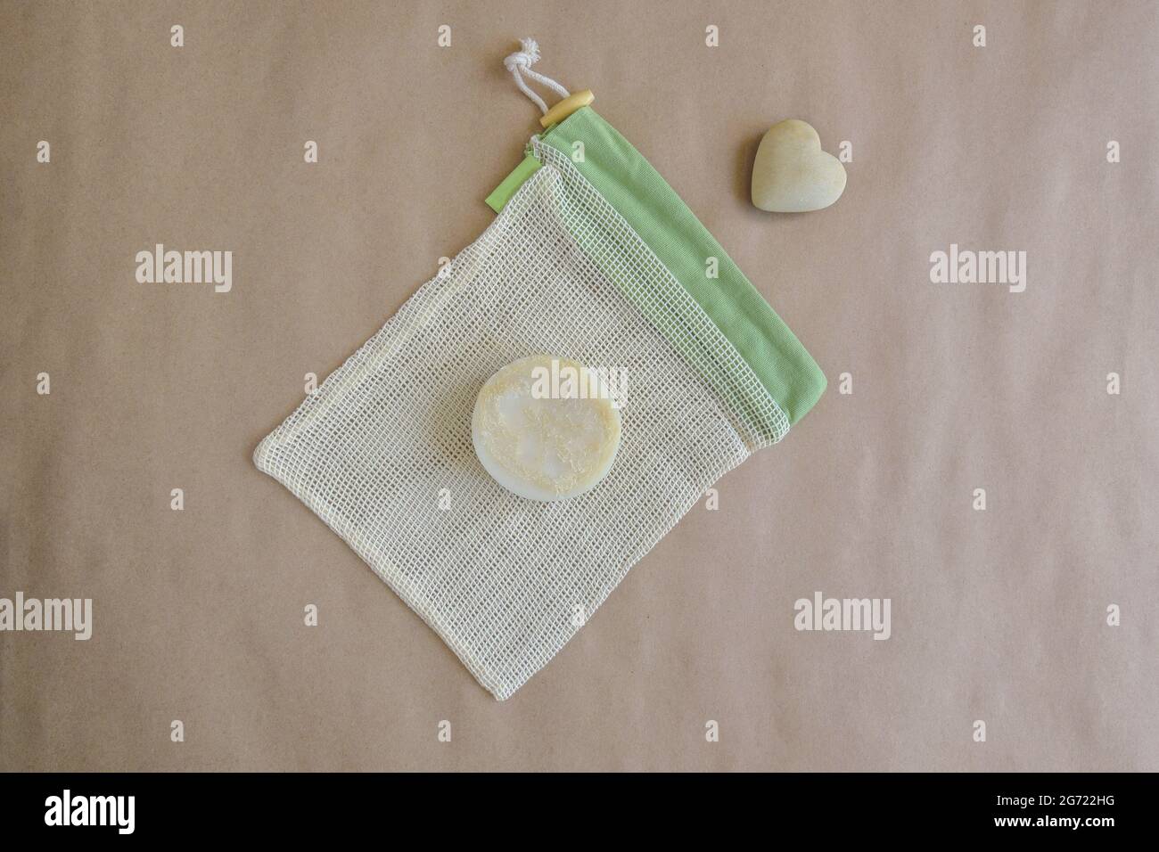 Round natural handmade soap on mesh packaging bag and souvenir stone ...