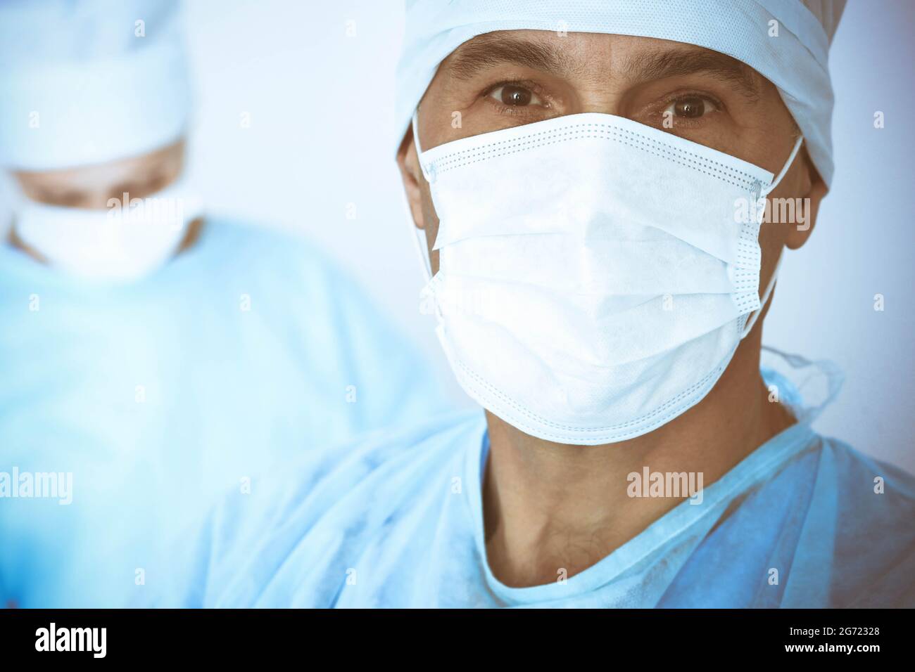 A male surgeon headshot, a group of surgeons is operating in the ...