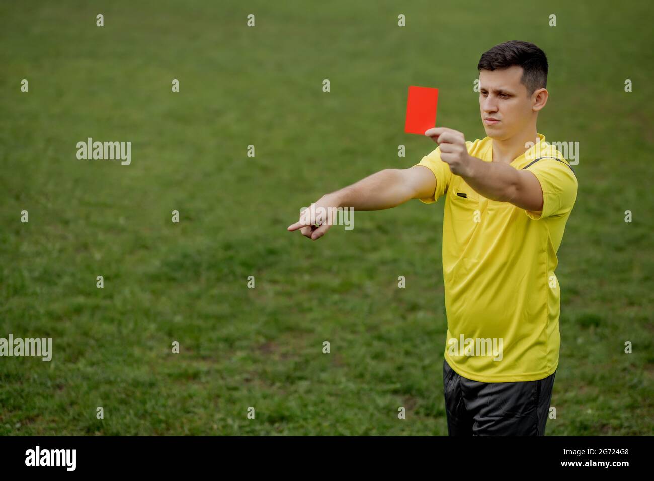 Angry football referee showing a red card and pointing with his hand on ...