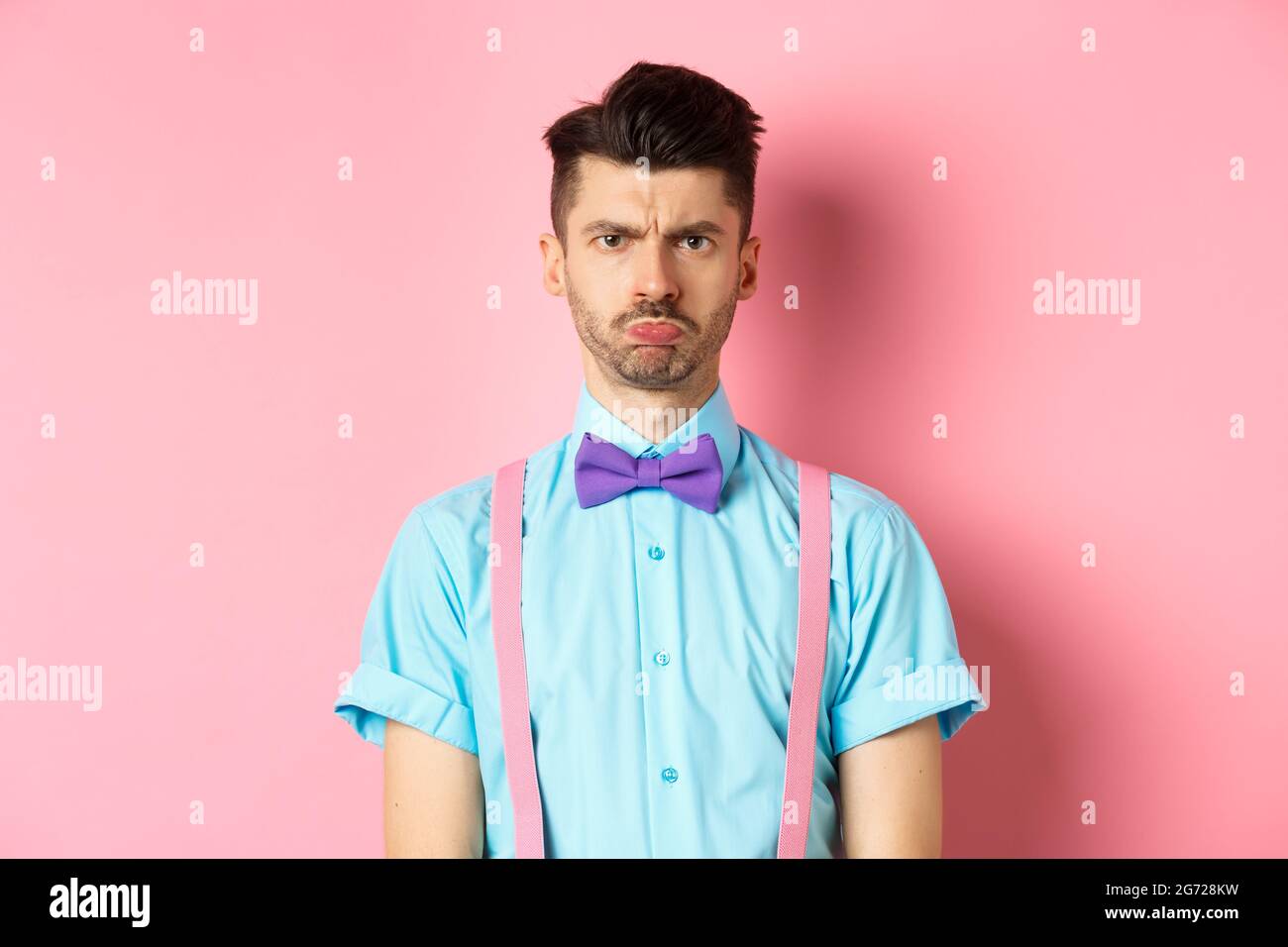 Sad and offended young man, frowning and pucker lips, looking angry at ...