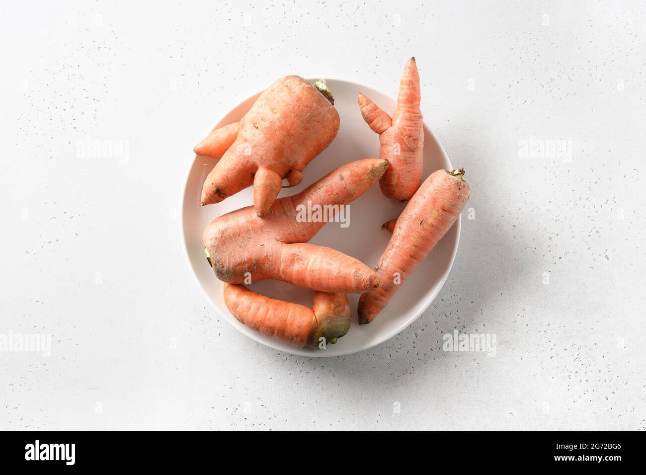 Abnormal ugly organic carrots in plate isolated on white background ...