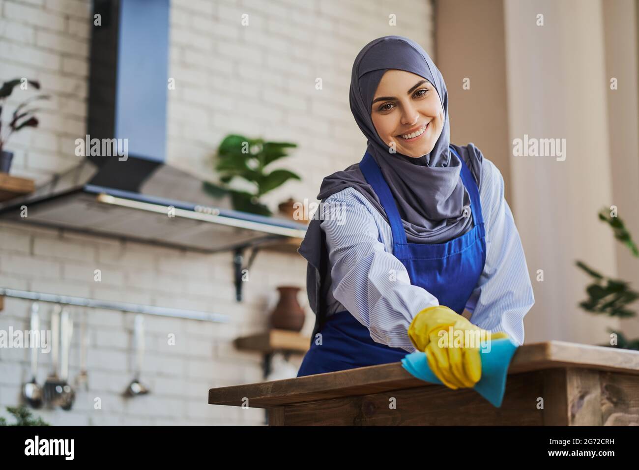 Beautiful Arabian housewife cleaning her house with a rag and gloves ...
