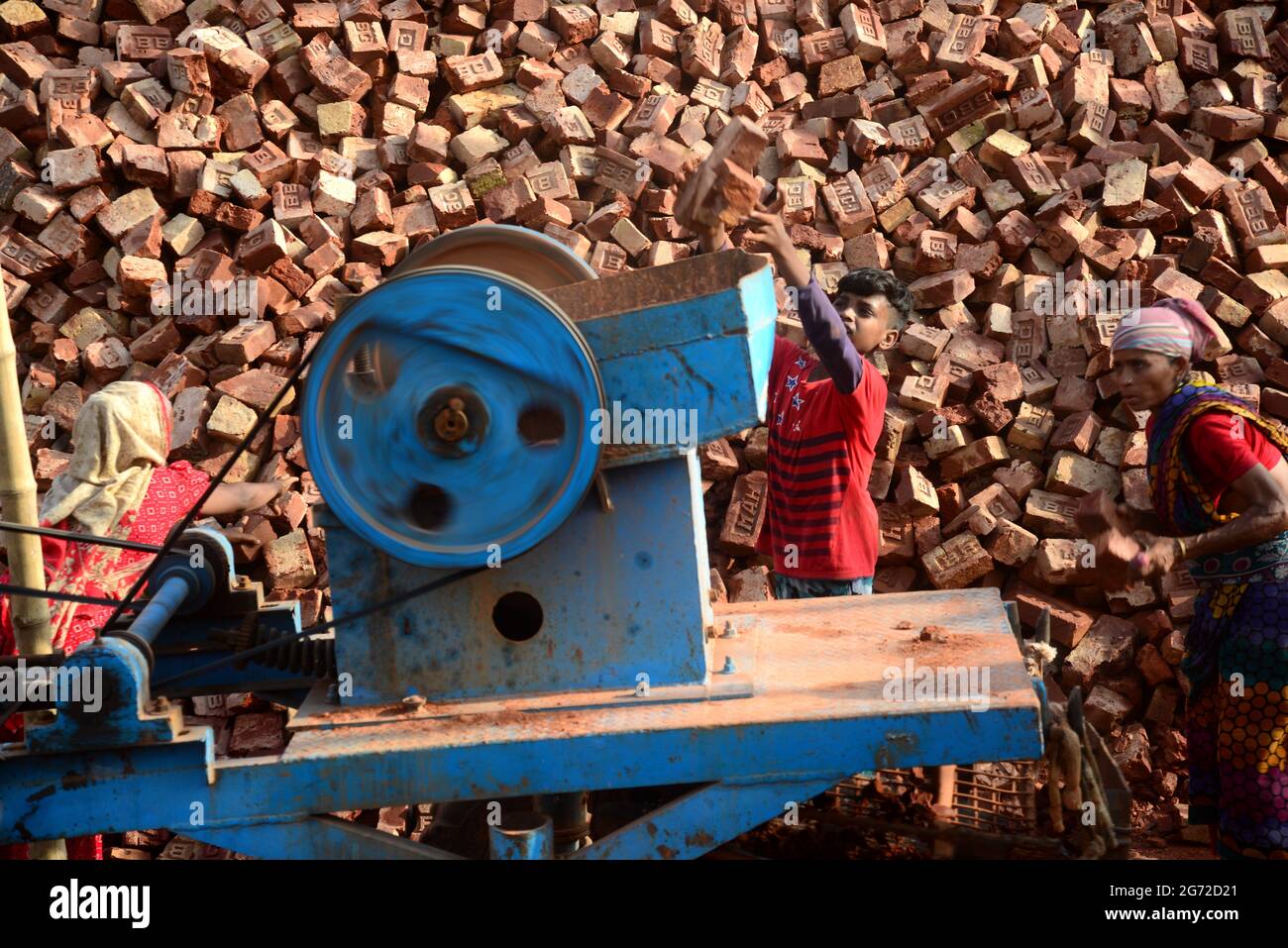 Bangladeshi day labor busy to crushing bricks with a machine during ...