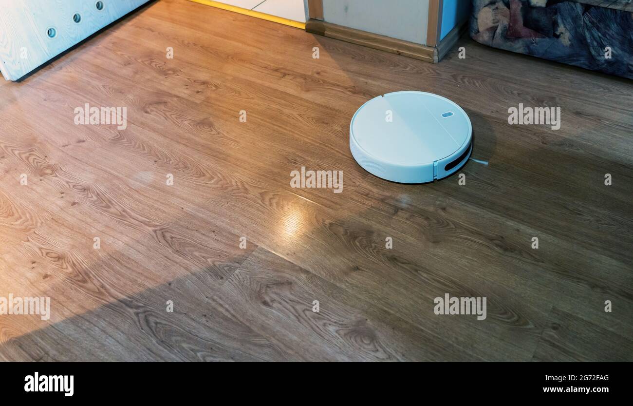 Robot vacuum cleaner and mop cleaning wooden surface in a room floor ...