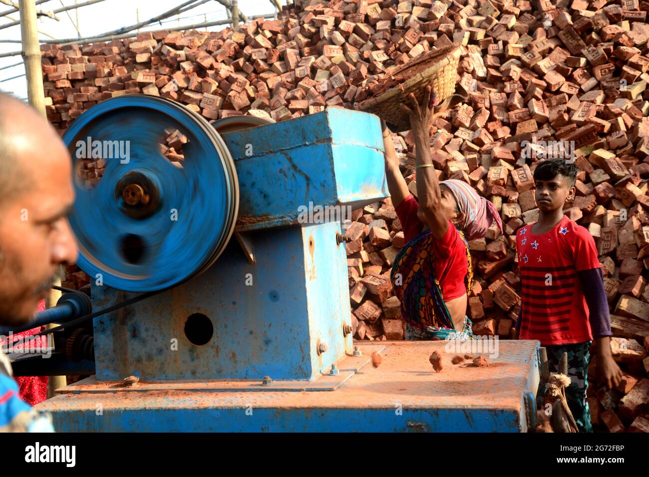 Bangladeshi day labor busy to crushing bricks with a machine during ...