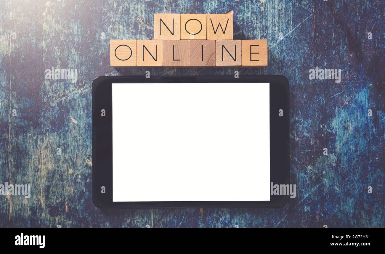 Now Online in Block Letters on a Blue Wooden Table with a Blank Tablet ...