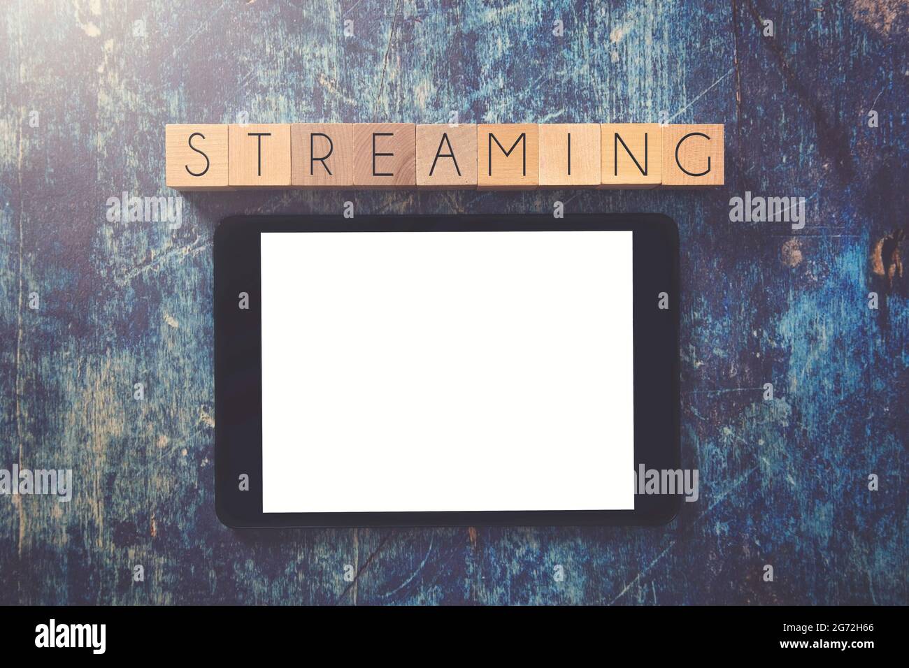 Streaming in Block Letters on a Blue Wooden Table with a Blank Tablet ...