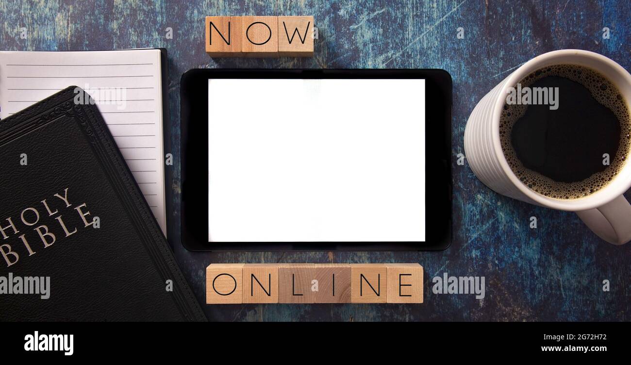 Now Online in Block Letters on a Wooden Table with a Bible and Tablet ...