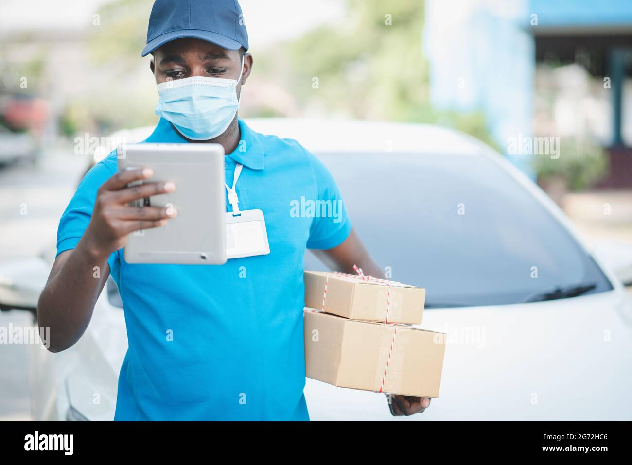 African delivery man wearing face mask and looking tablet with holding ...