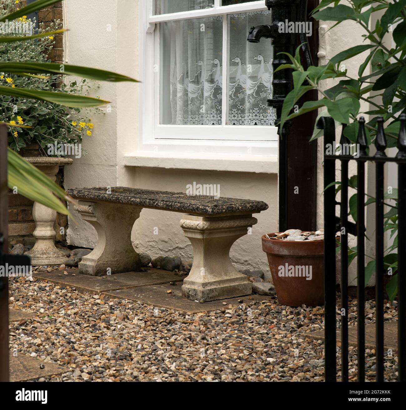 Small stone bench seat in a small garden Stock Photo - Alamy