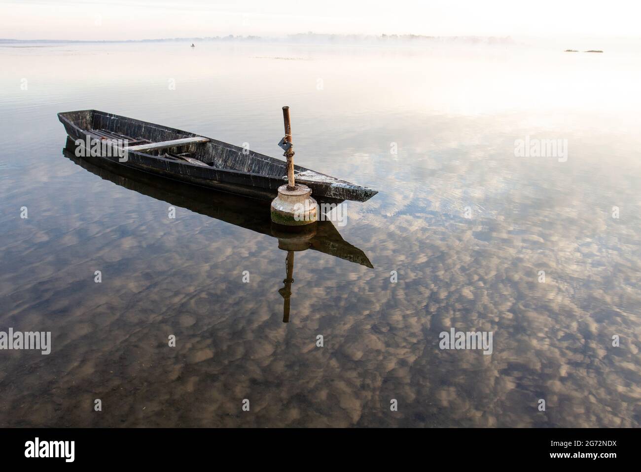 Village boat on the translucent lake in the early misty morning Stock ...