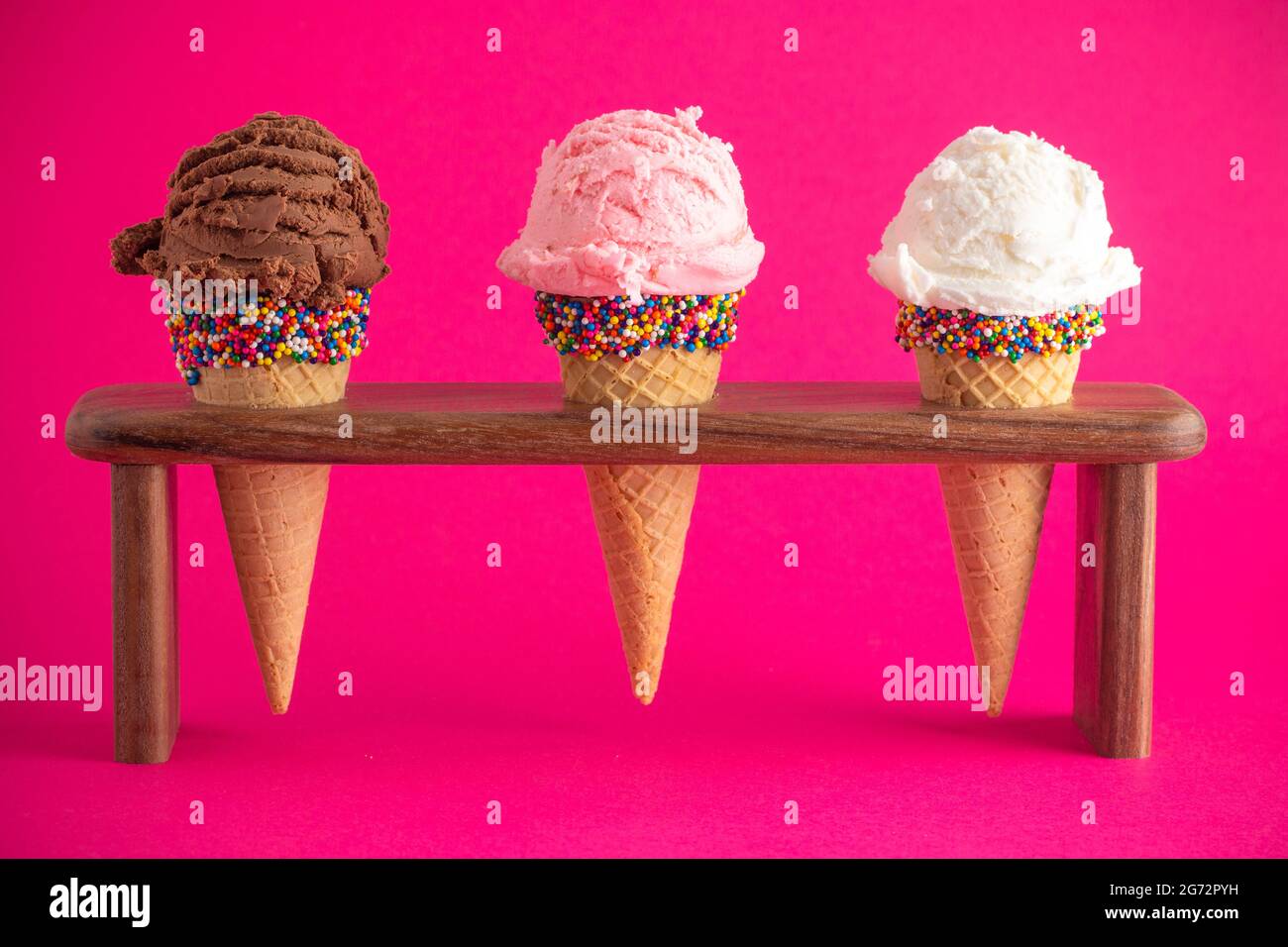 Chocolate Strawberry And Vanilla Ice Cream Cones With Sprinkles On A Bright Pink Background
