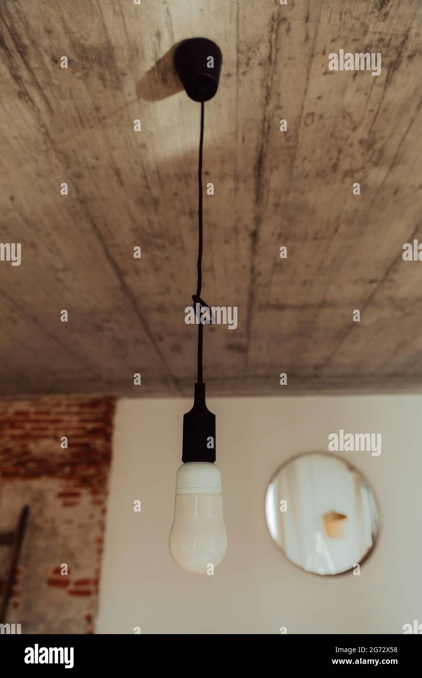 Low angle shot of a loft-style hanging lamp and a round-shaped mirror ...