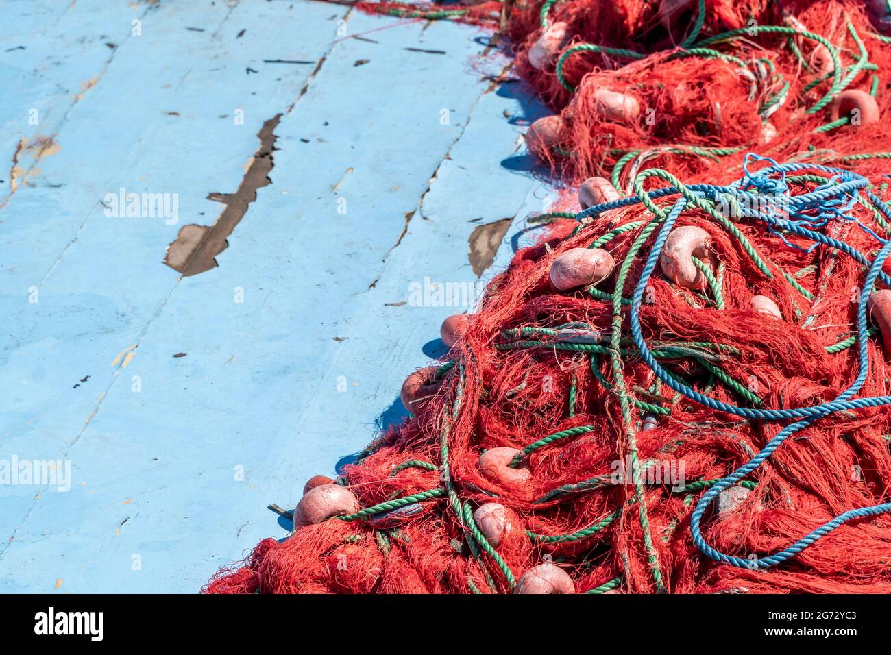 pile of red fishing nets on wooden background of a boat with copy space ...