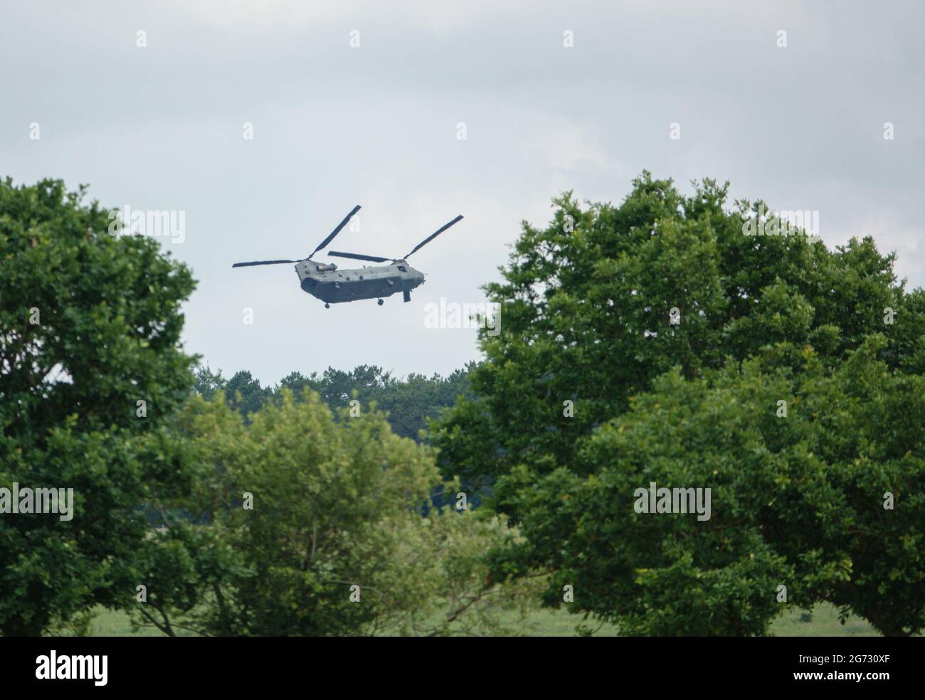 RAF Chinook tandem-rotor CH-47 helicopter flying fast and low, banking ...