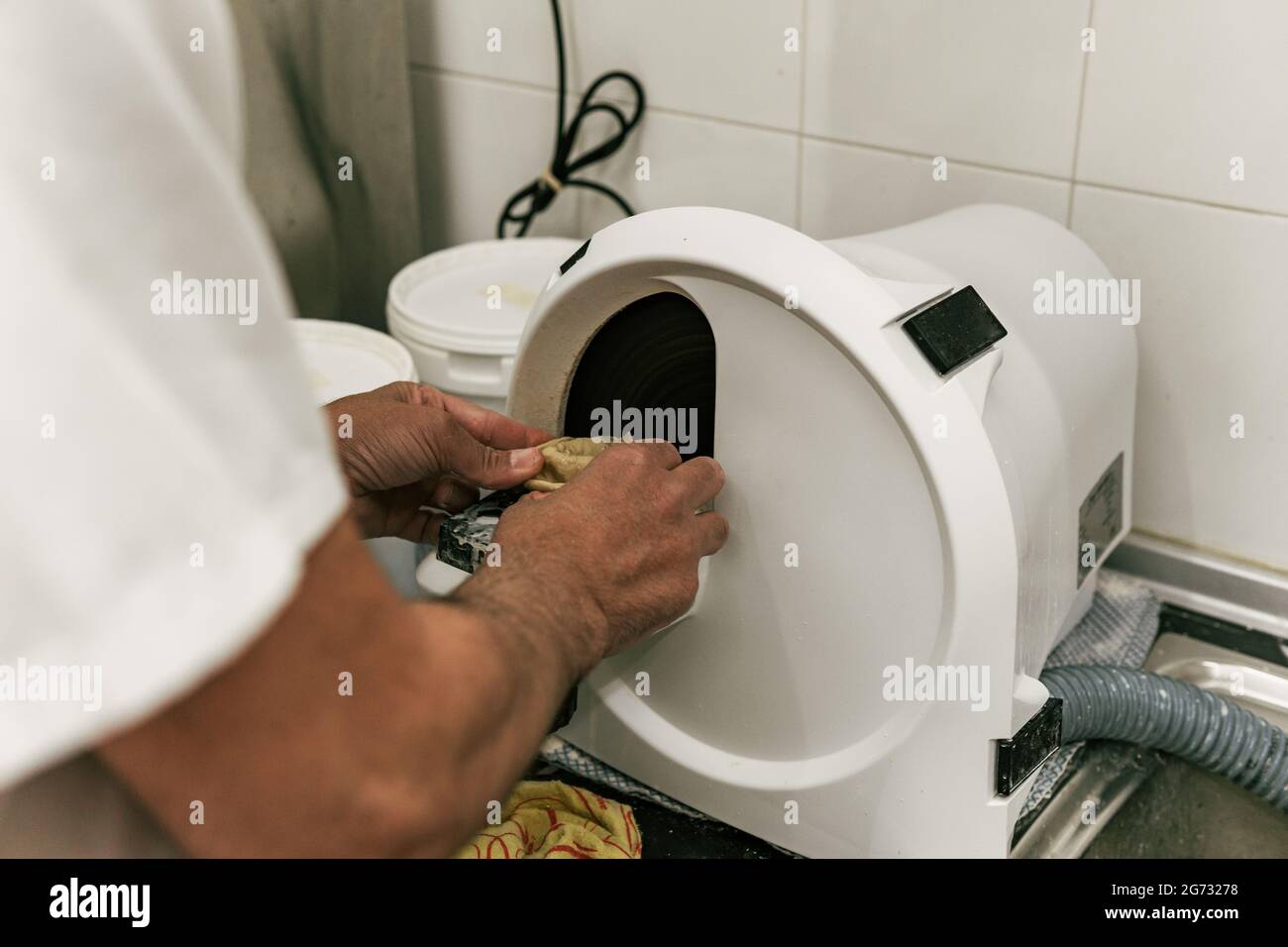 Technician inserting a dental plaster cast into a trimmer Stock Photo ...