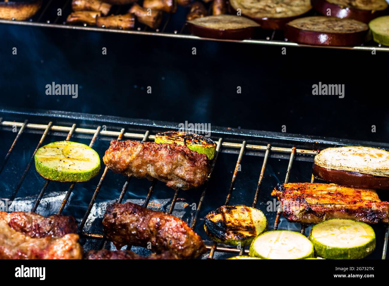 Grilling meat rolls called mici or mititei with vegetables on char ...