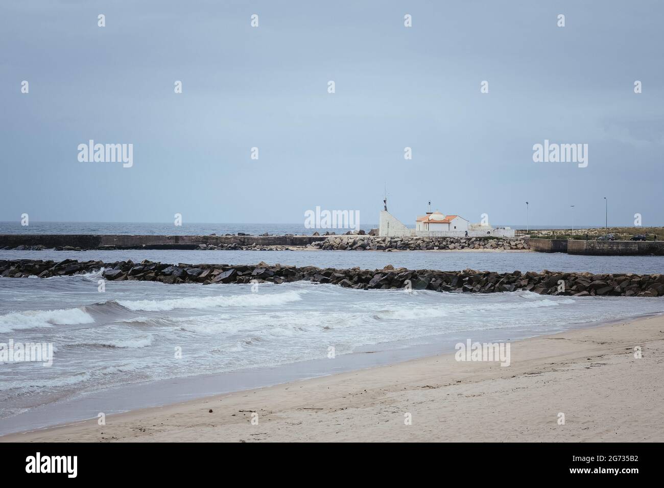 Beach and rocky platform projecting to the sea with houses in the ...