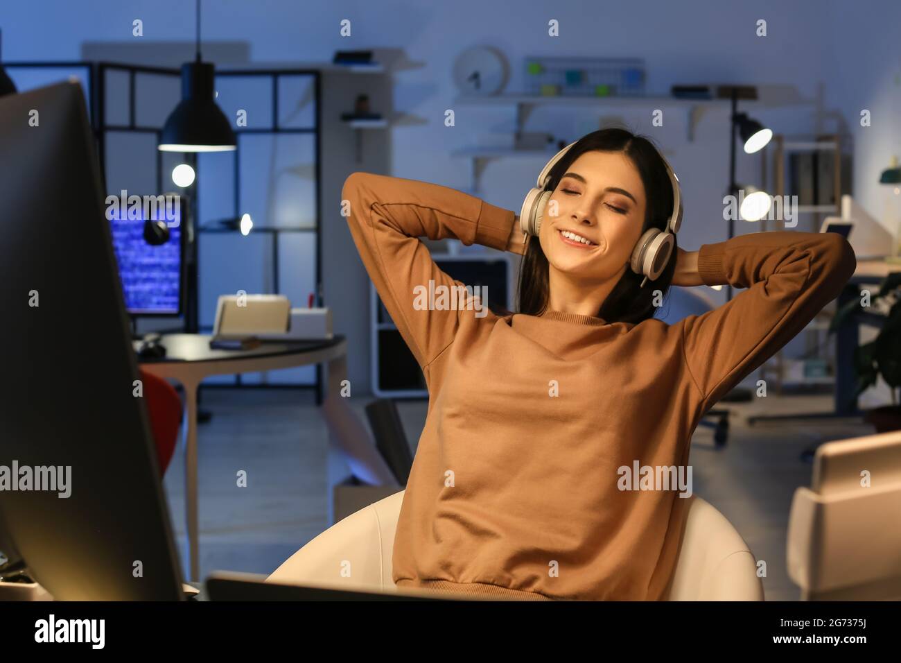 Female programmer relaxing in office at night Stock Photo - Alamy
