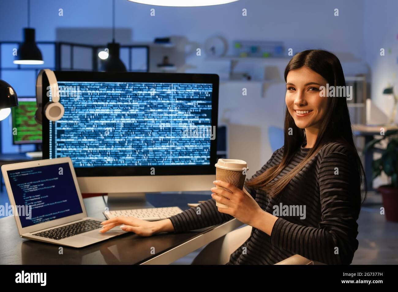 Female programmer working with laptop in office at night Stock Photo ...