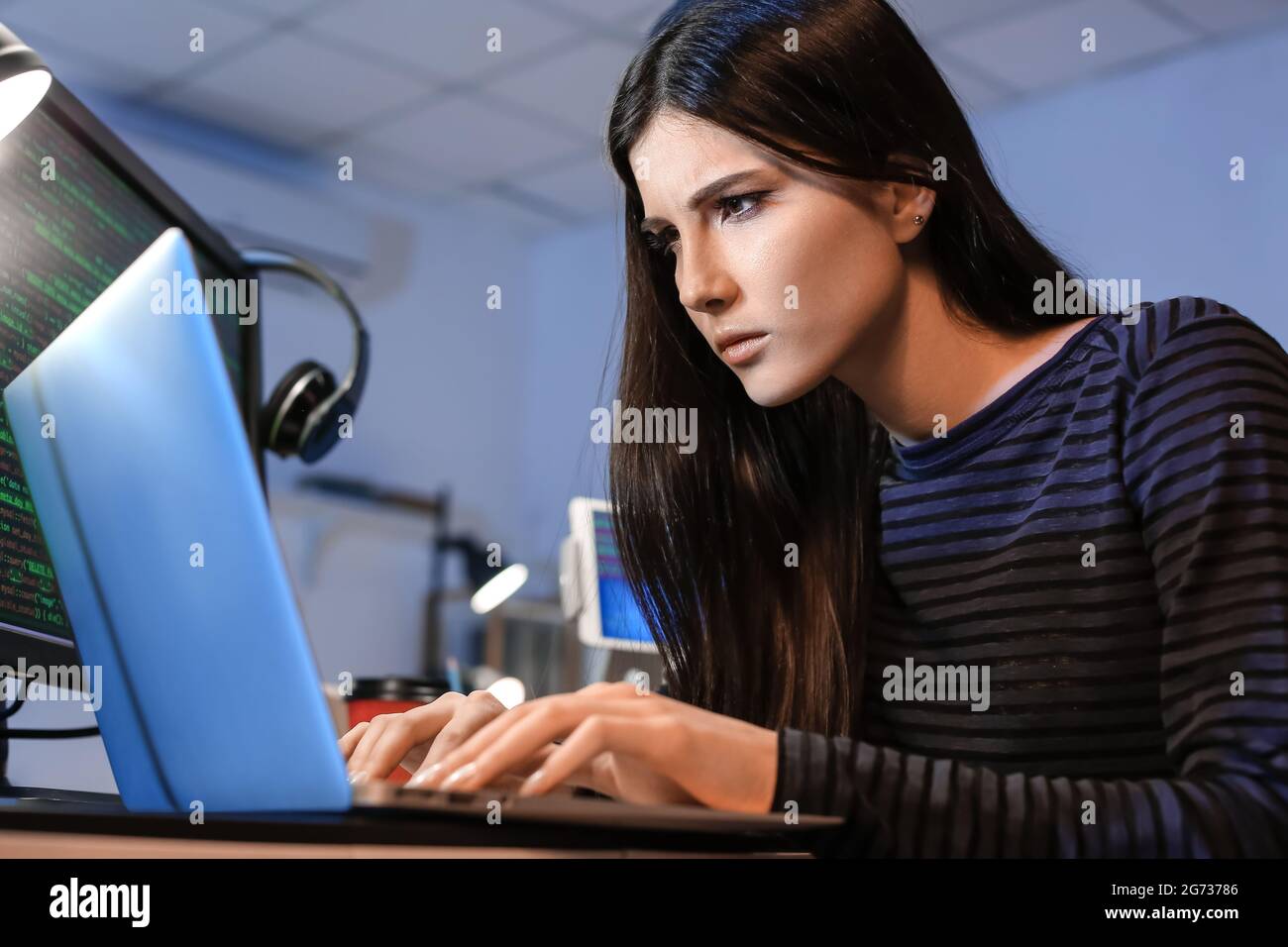 Female programmer working with laptop in office at night Stock Photo ...