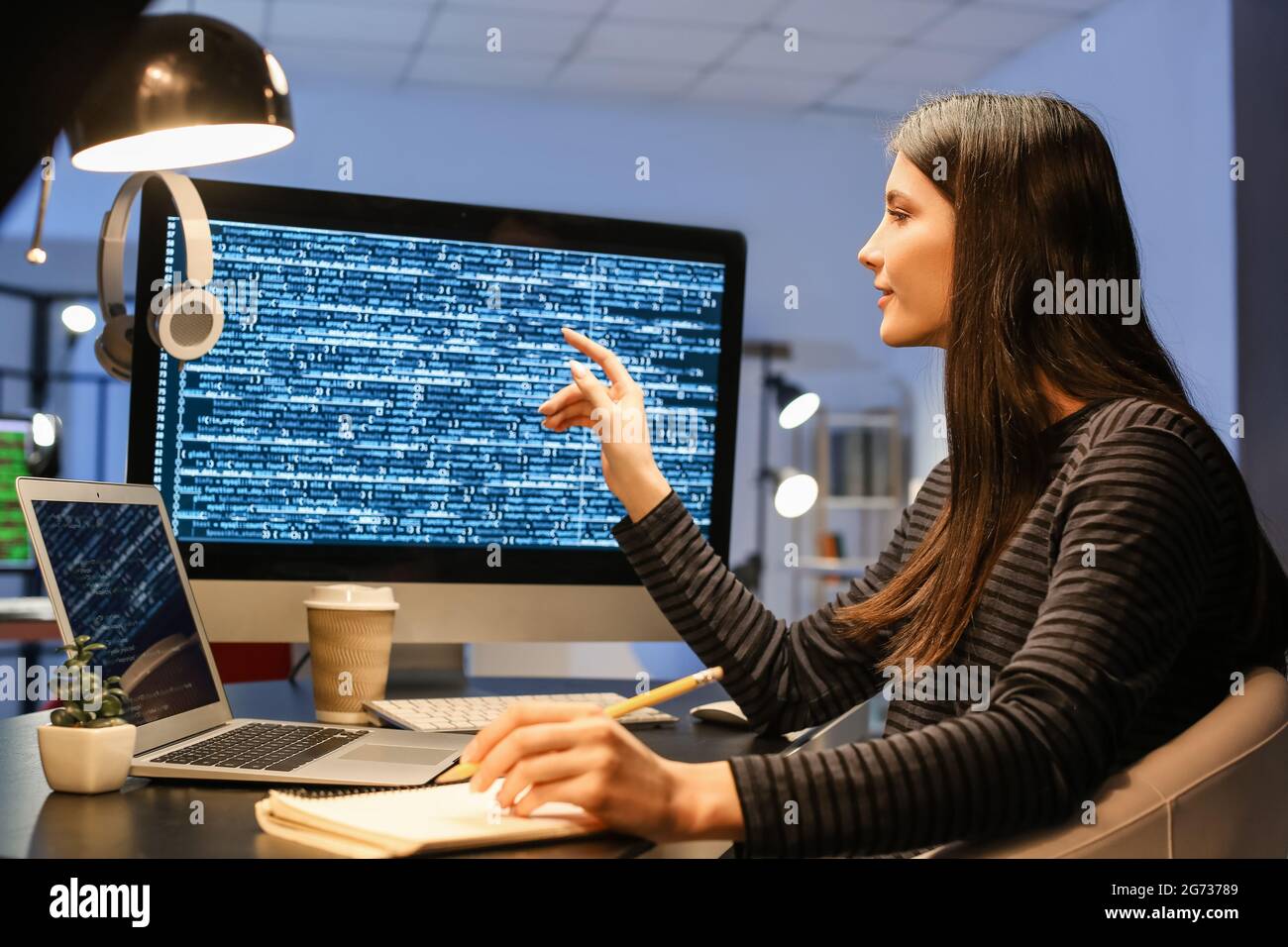 Female programmer working with laptop in office at night Stock Photo ...