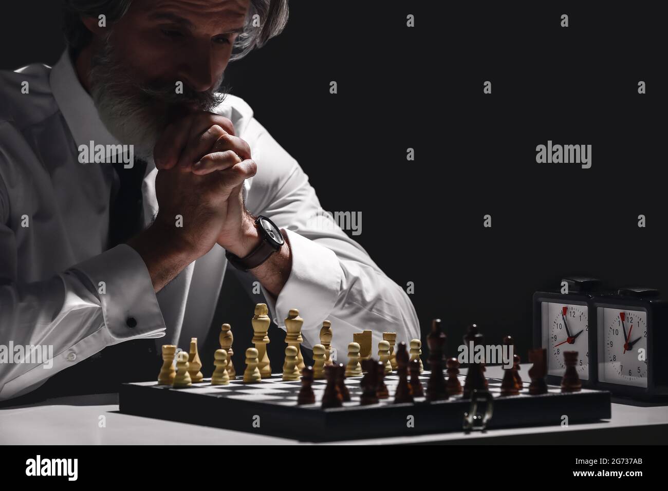 Senior man playing chess on dark background Stock Photo - Alamy