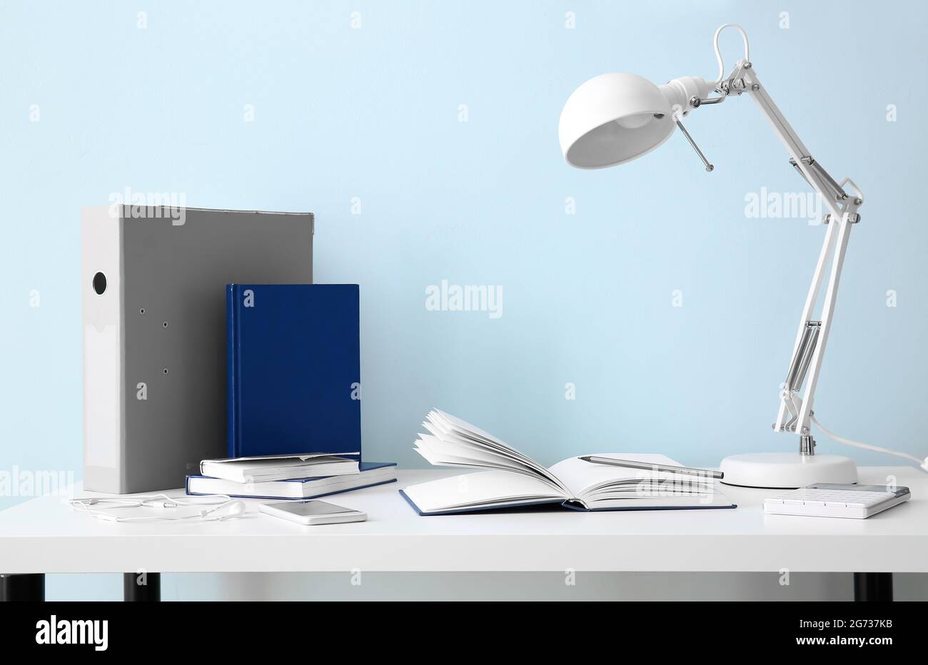 Modern workplace with notebooks and lamp near color wall Stock Photo ...