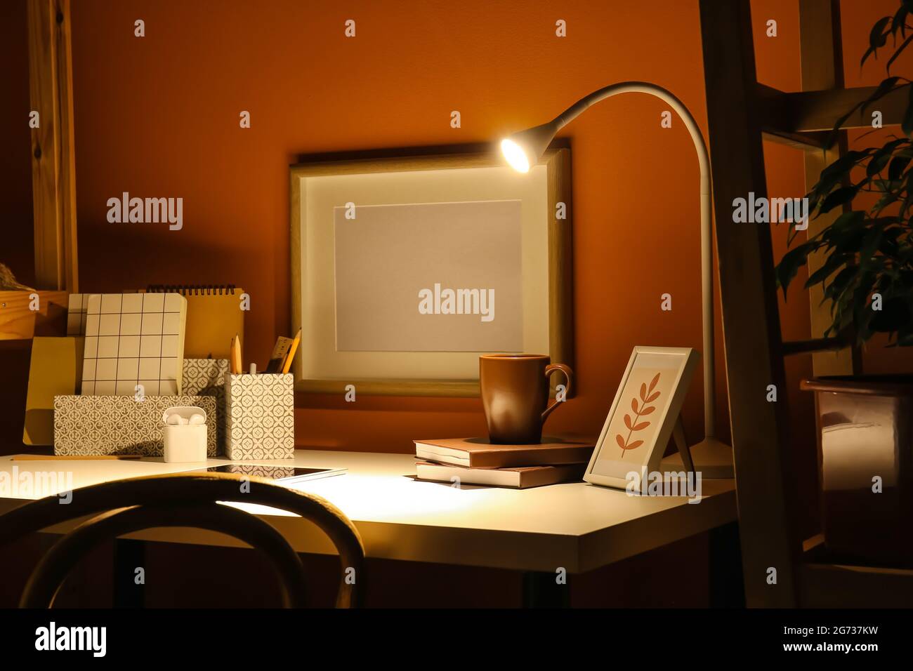 Modern workplace with glowing lamp in dark room Stock Photo - Alamy