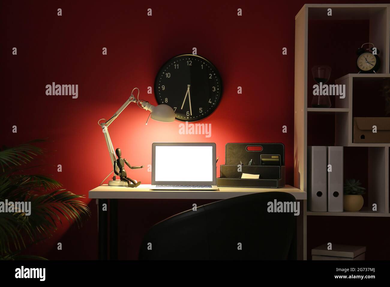 Modern workplace with laptop and glowing lamp in dark room Stock Photo ...