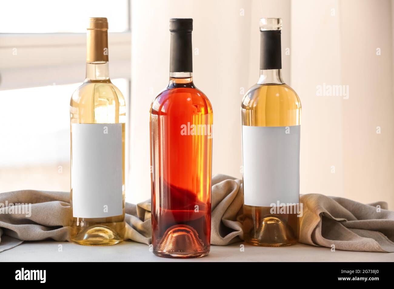 Bottles of exquisite wine on light table in room Stock Photo - Alamy