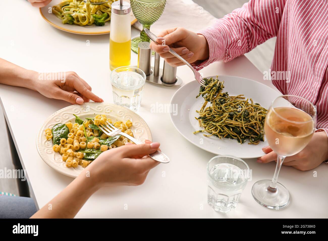 Women eating healthy pasta at table Stock Photo - Alamy