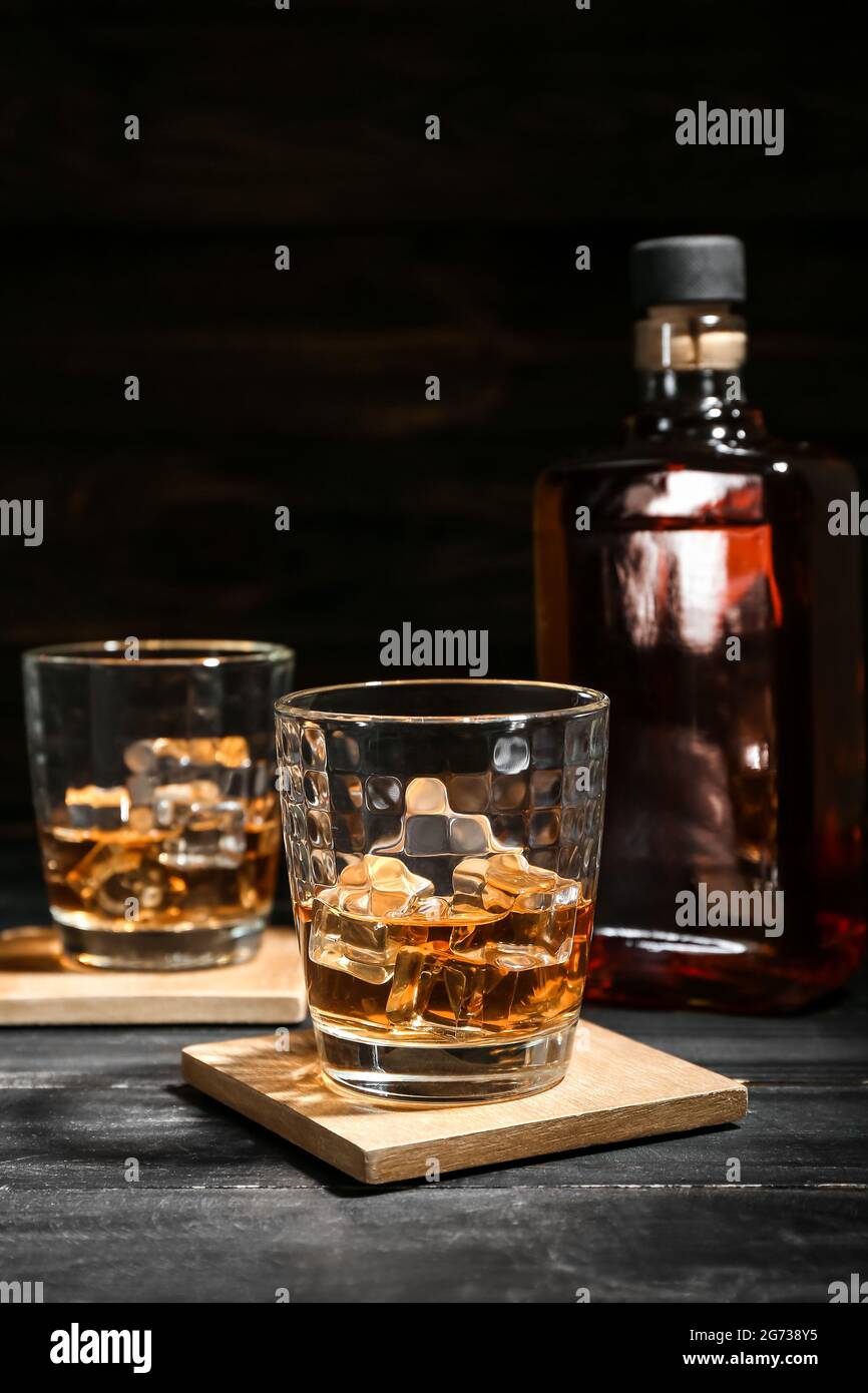 Bottle and glasses of cold whiskey on dark wooden background Stock ...