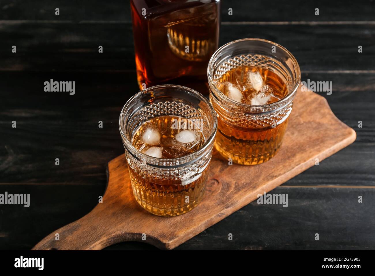 Bottle and glasses of cold whiskey on dark wooden background Stock ...