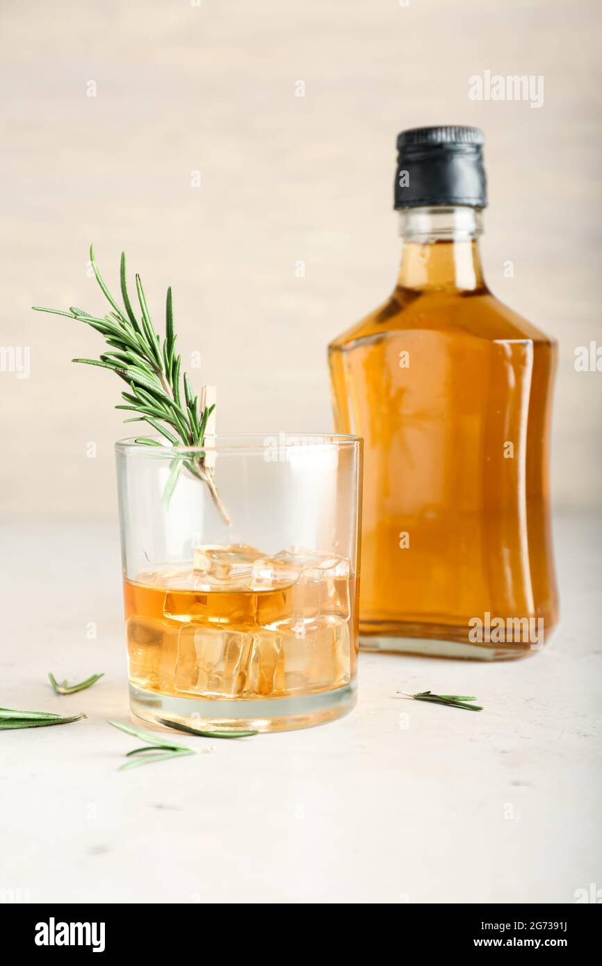 Bottle and glass of cold whiskey on light background Stock Photo - Alamy