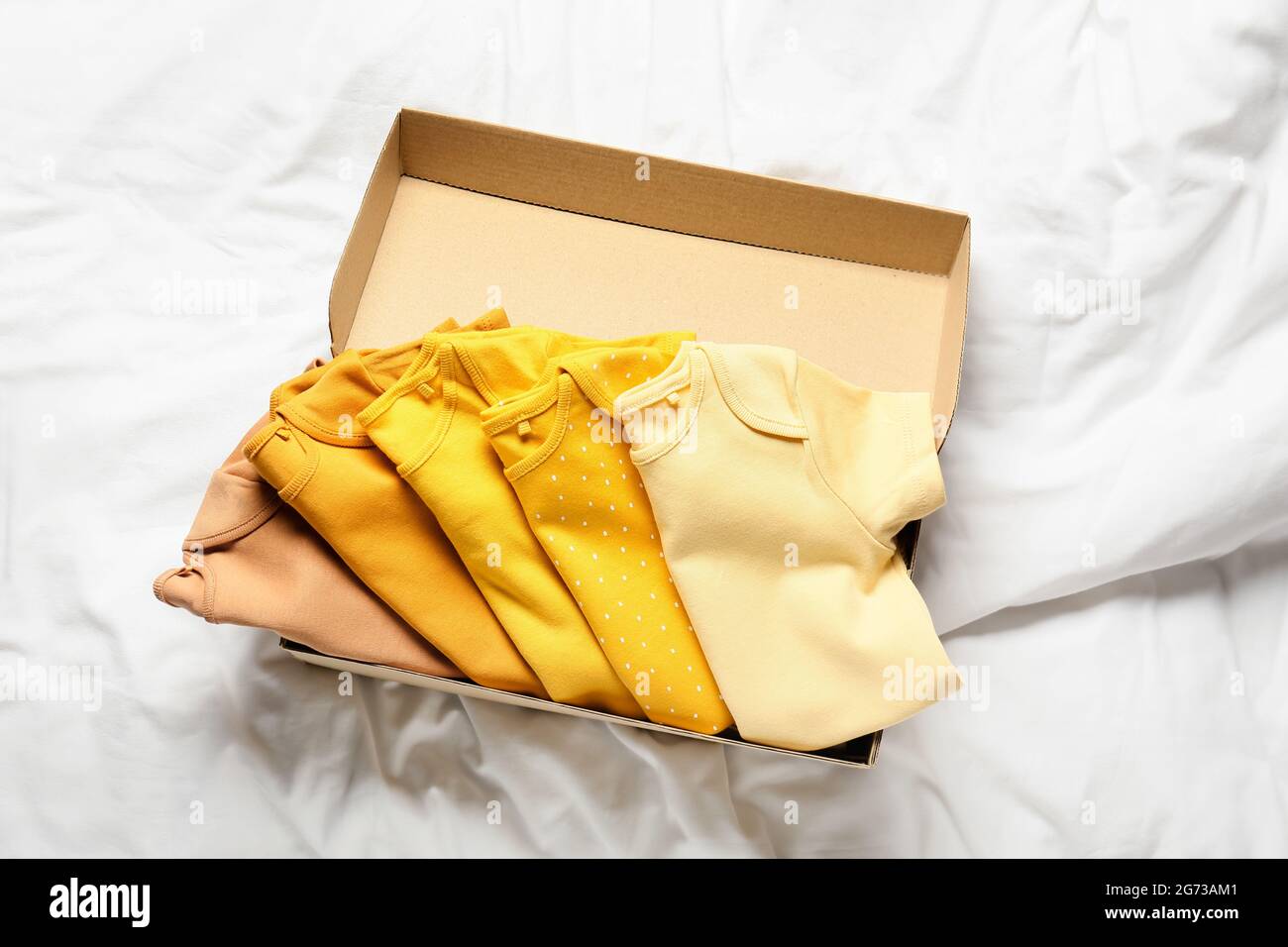 Box with baby clothes on bed Stock Photo - Alamy