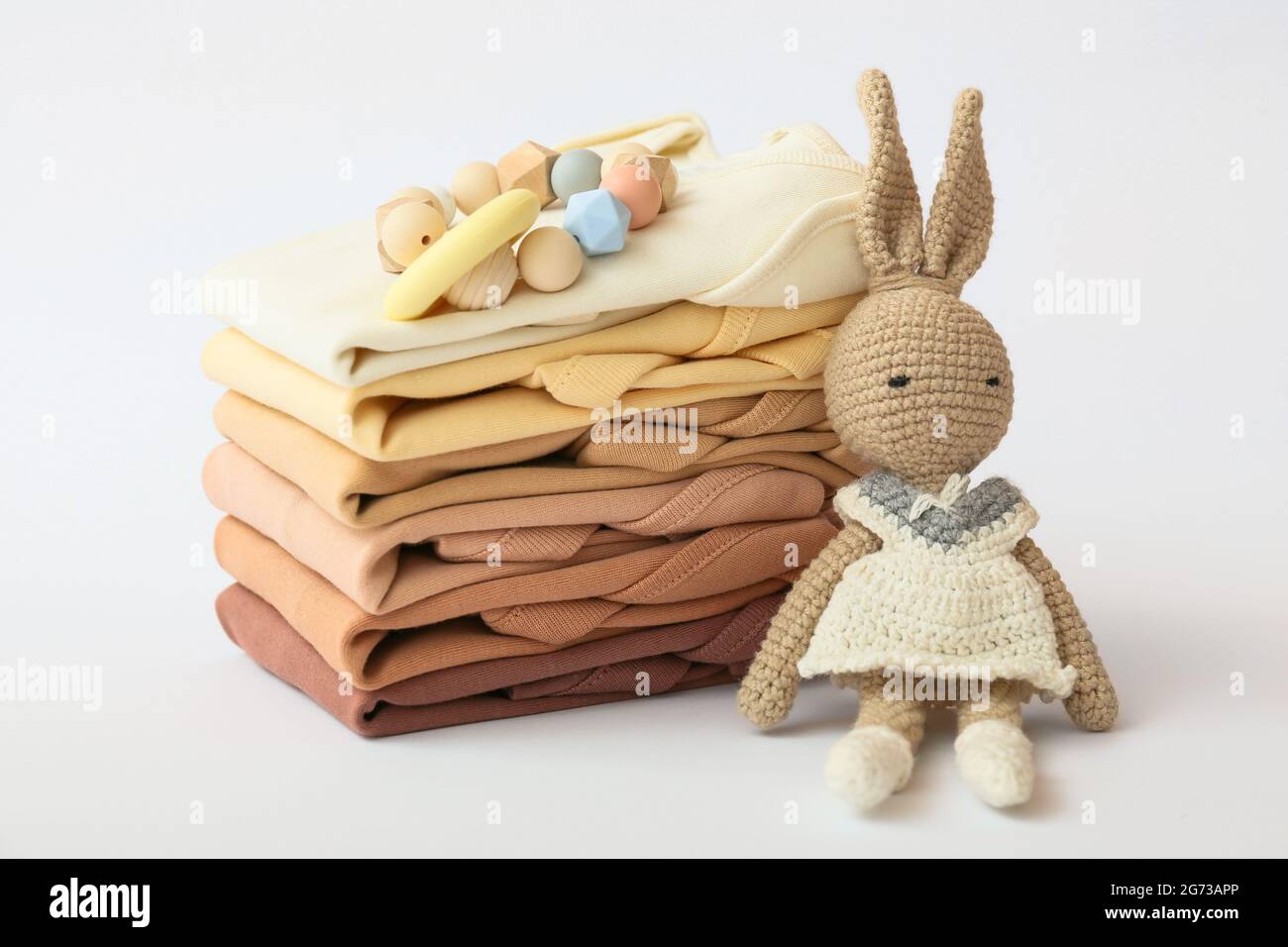 Stack of baby clothes, knitted toy and teether on grey background Stock ...