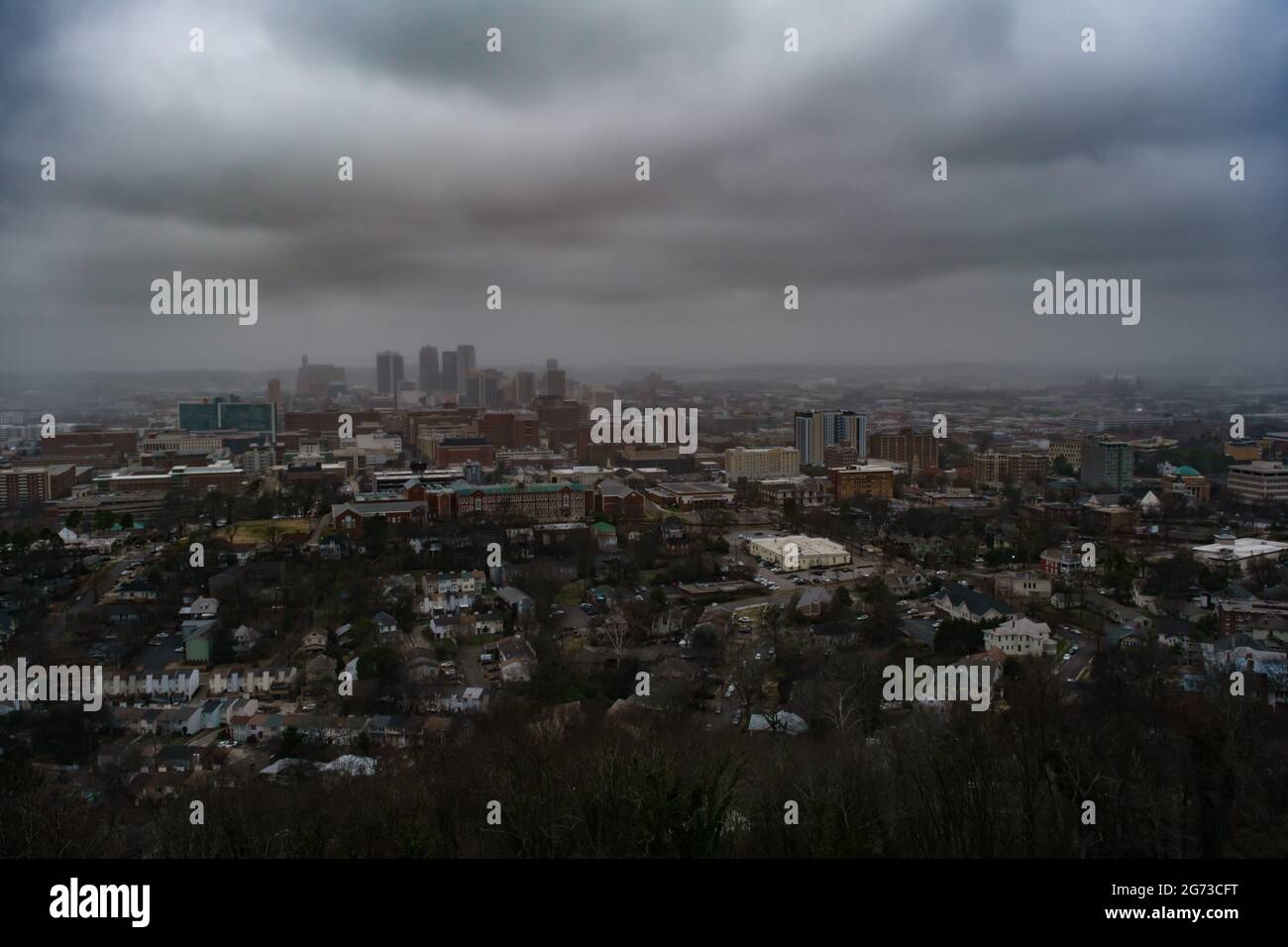 Landscape of a city covered in trees and buildings under a cloudy sky ...