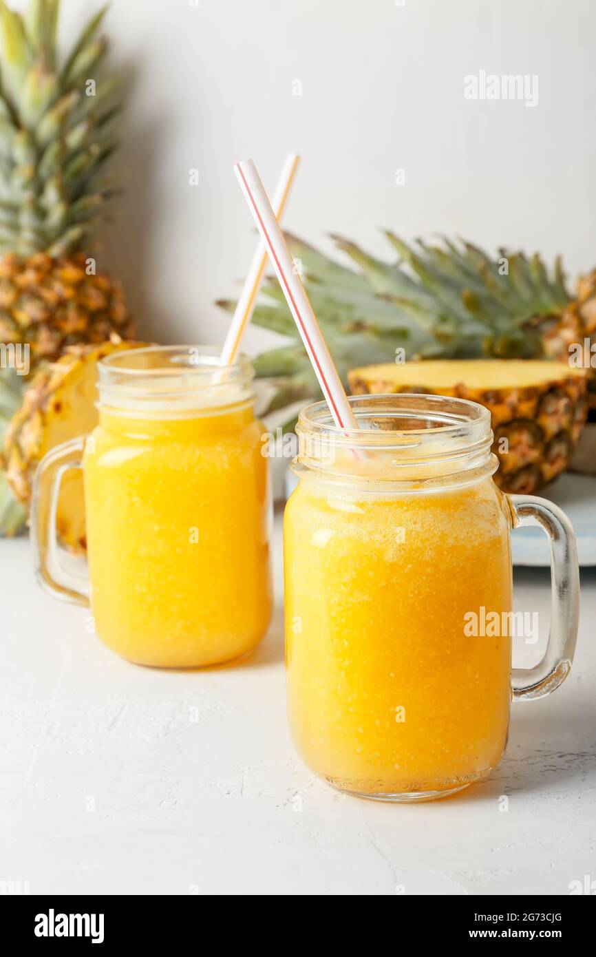 Mason jars of tasty pineapple smoothie on light background Stock Photo ...
