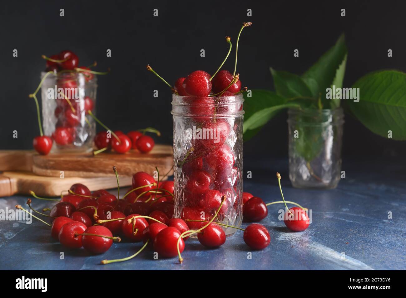 Jar with sweet cherry on dark background Stock Photo - Alamy