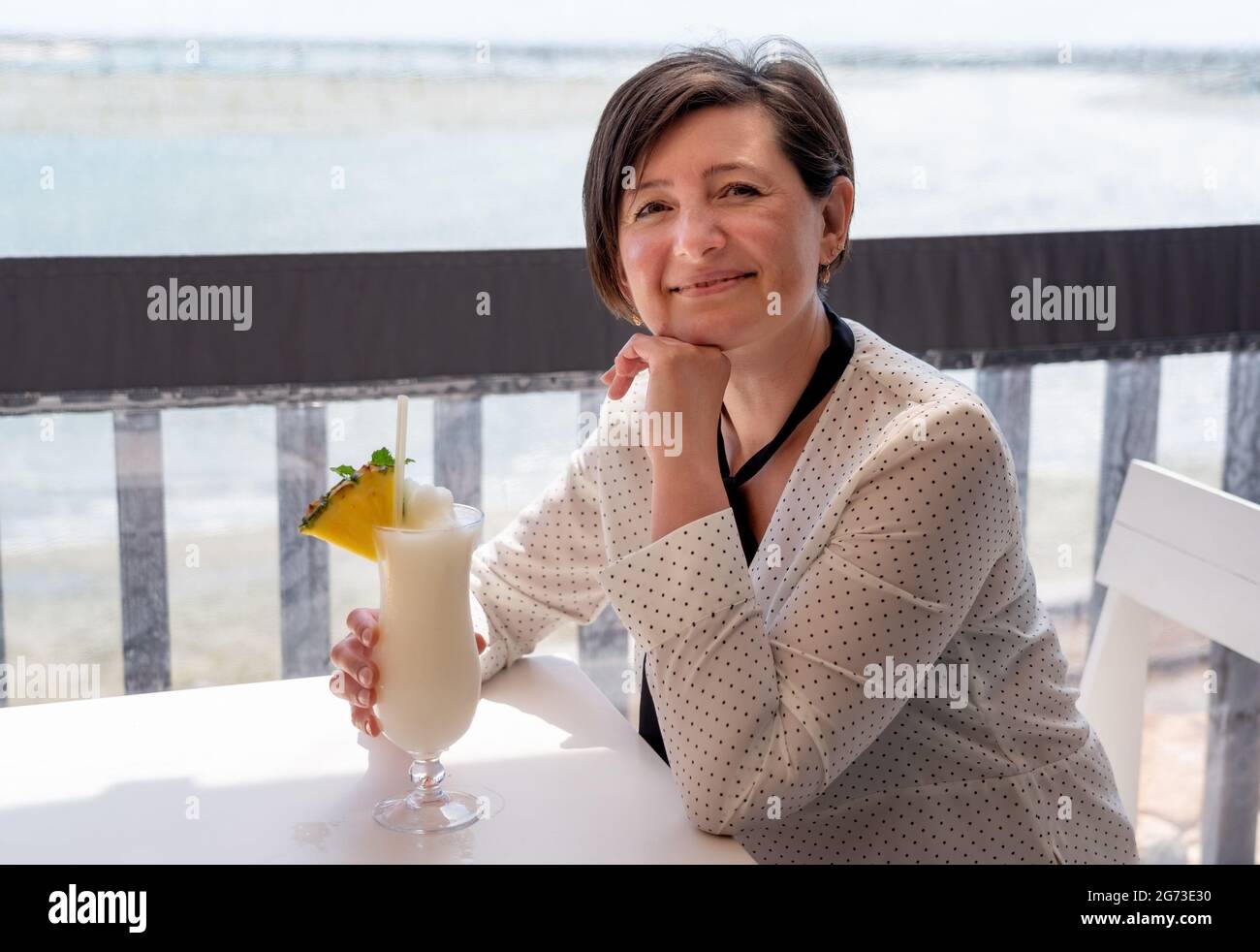 Middle-aged woman, in a bar, drinks a fruit coconut cocktail, with a ...