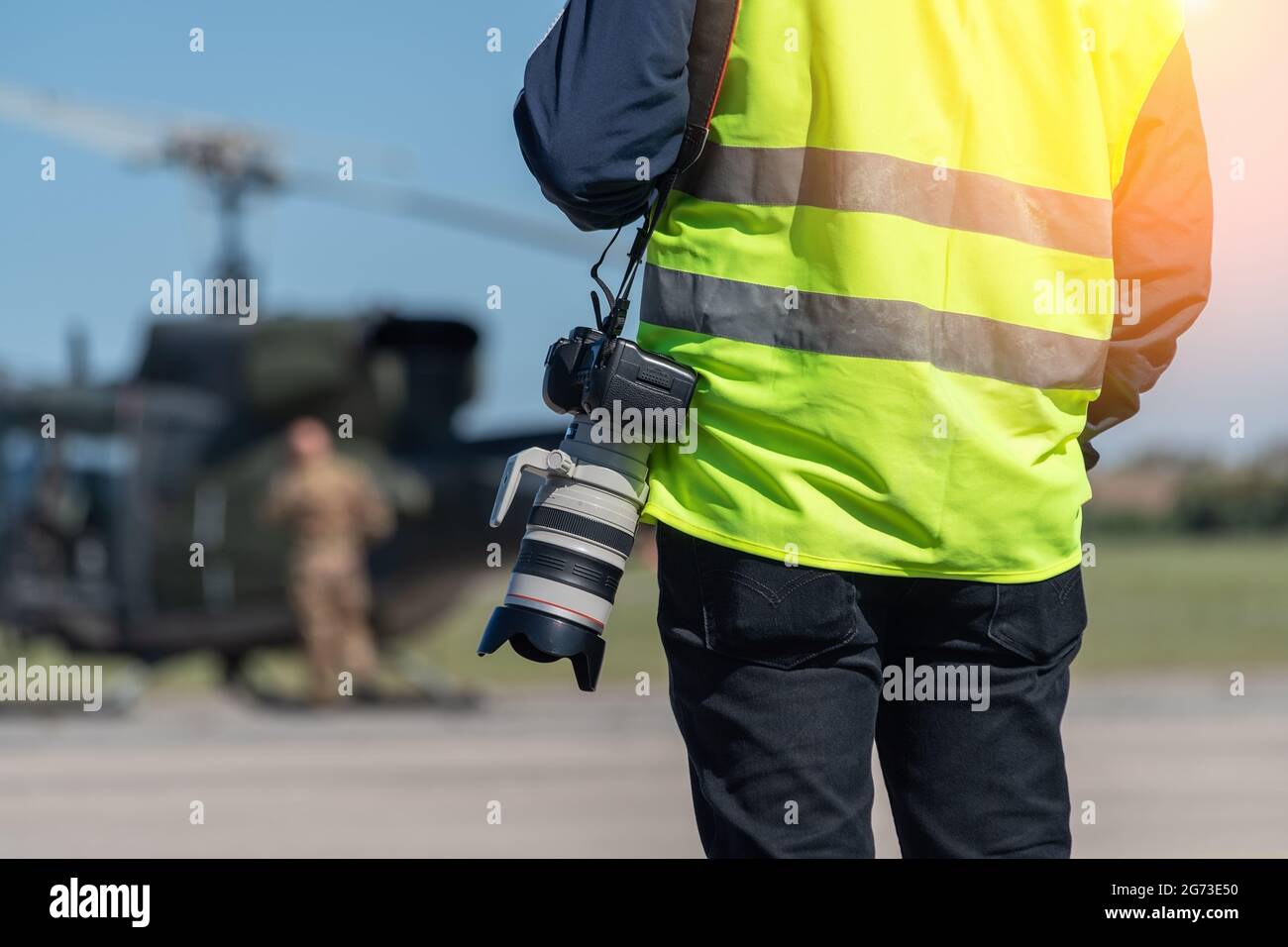 A military photographer, a reporter, in a signal yellow vest, ready to ...