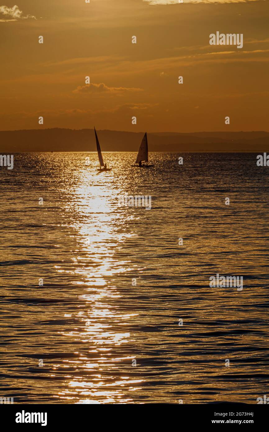 Sailing dinghies and streak of sunlight going across the channel Stock ...